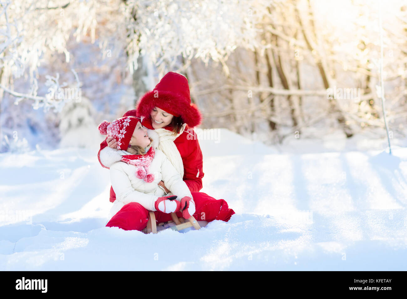 Mother and baby on sleigh ride. Child and mom sledding. Toddler kid ...