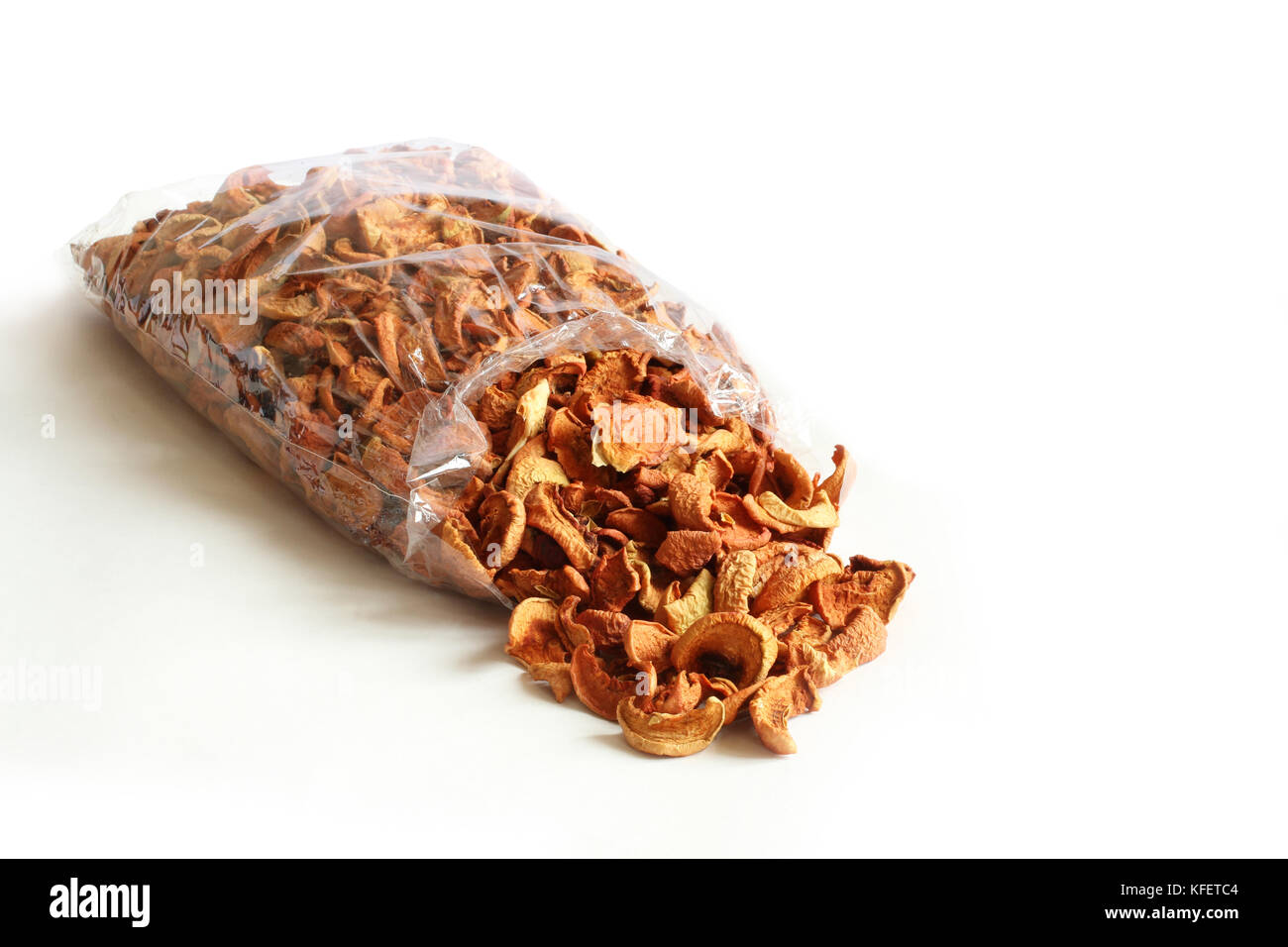 Dried pieces of apples poured out of a transparent package against ...