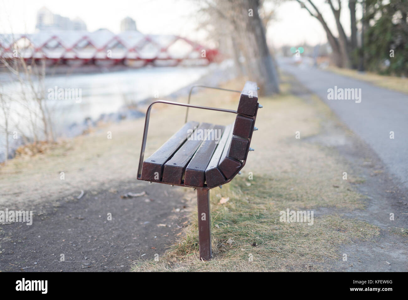 Park bench by the Bow River in Calgary with the Peace Bridge in the ...