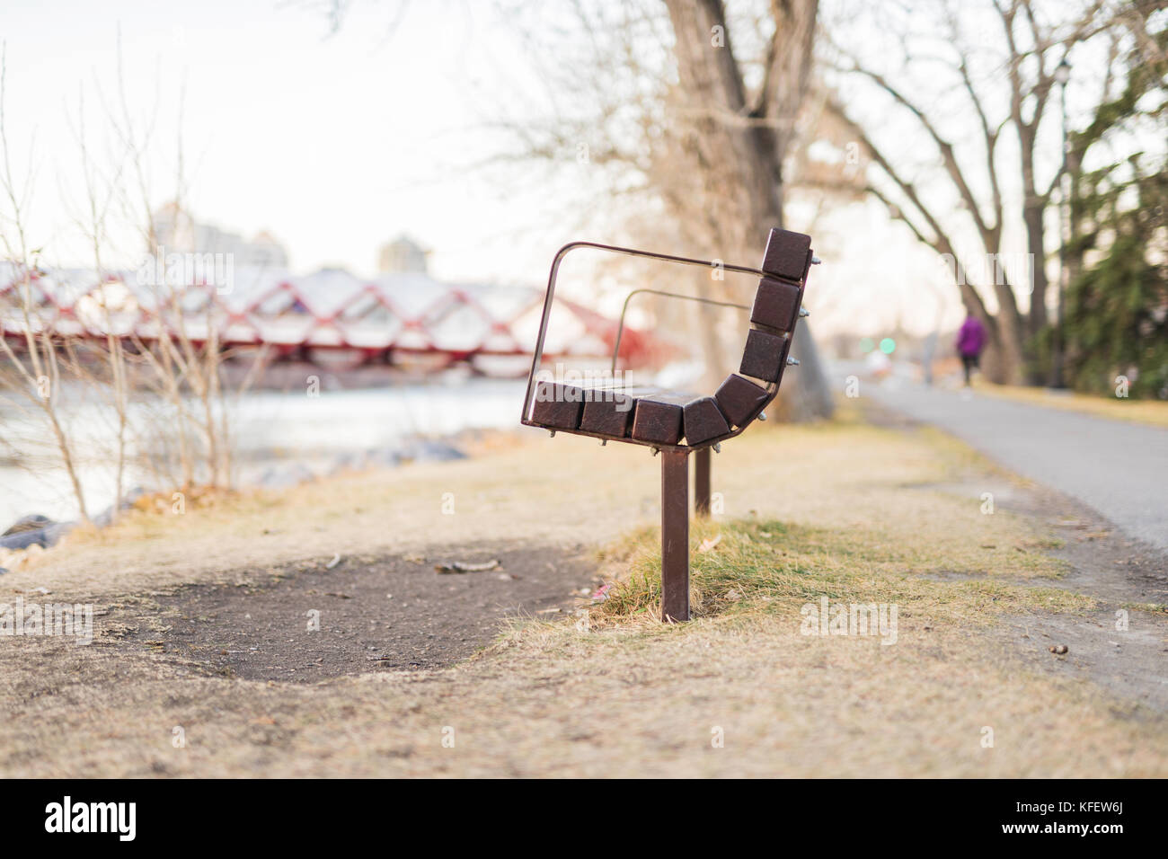 Park bench by the Bow River in Calgary with the Peace Bridge in the ...