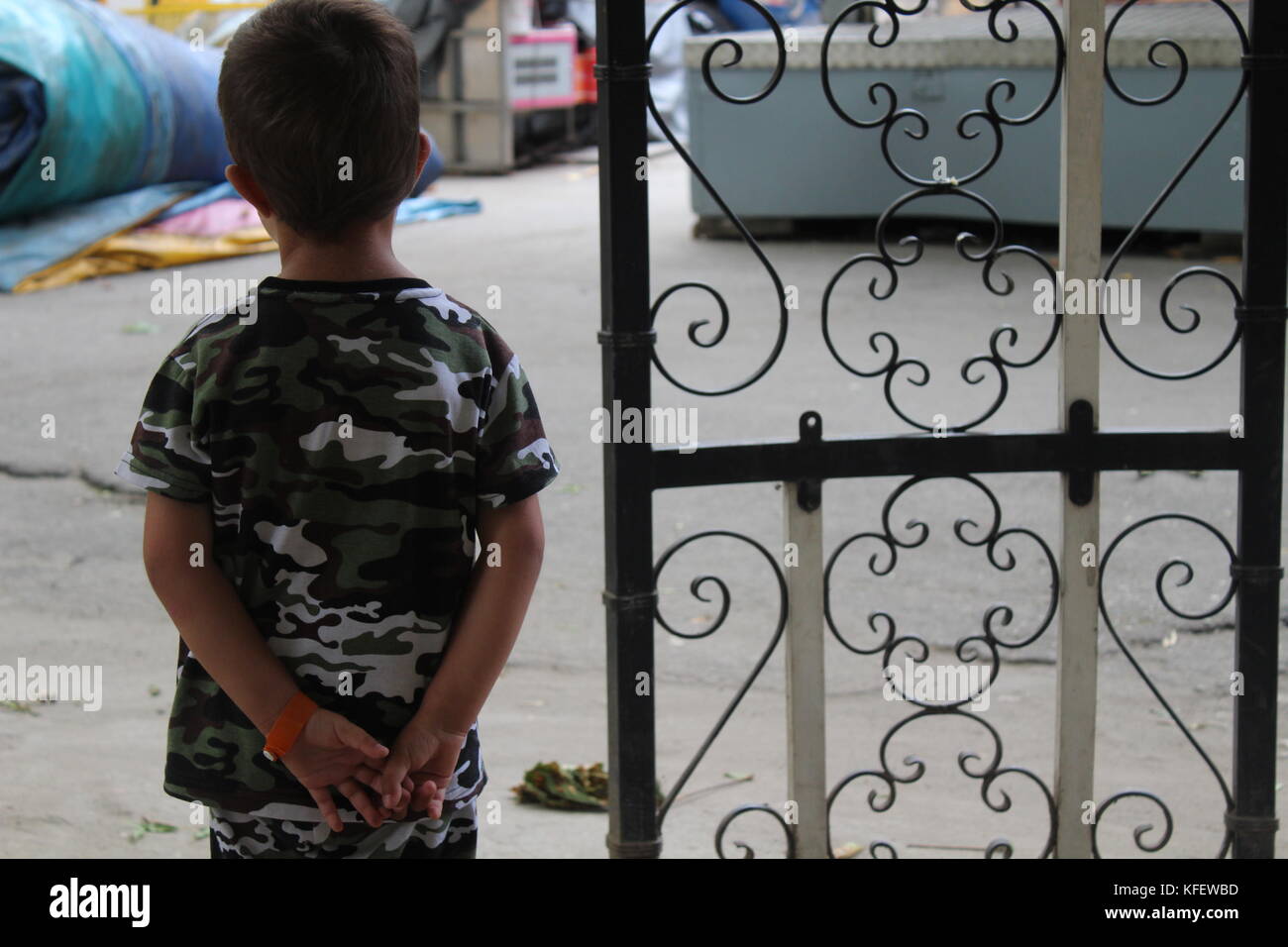 Lonely boy waiting on a gate holding hands Stock Photo - Alamy