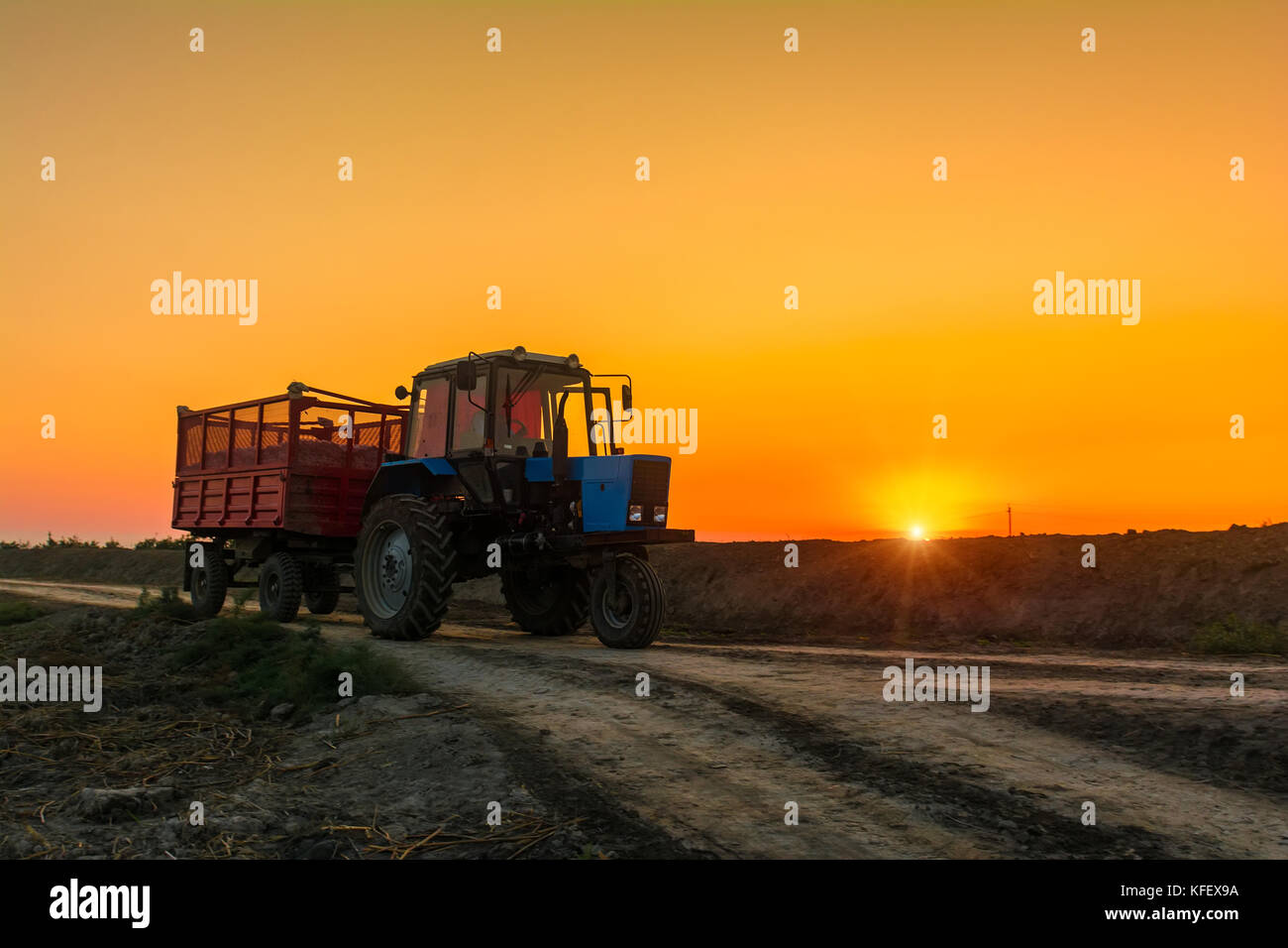 Farm tractor with a trailer on country road Stock Photo - Alamy