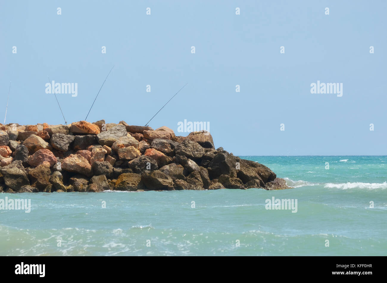 Summertime scene. Fishing rods on the rocks. Breakwater at the beach of ...