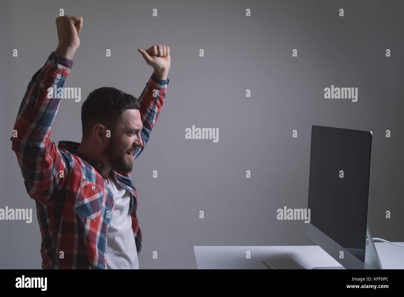 Businessman cheering in front of his computer in the office Stock Photo ...