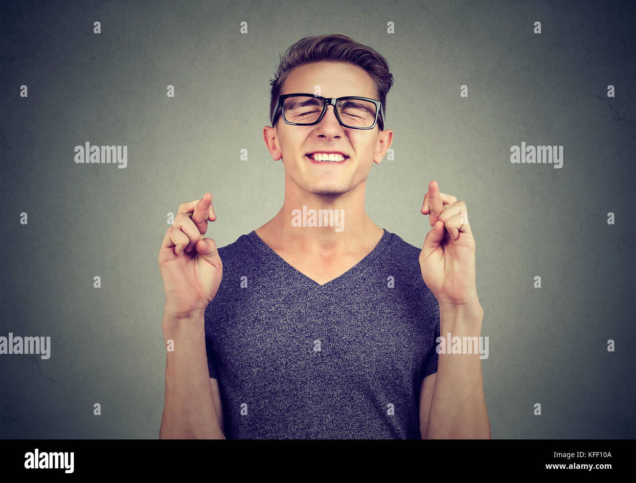 Closeup portrait hopeful man crossing his fingers, eyes closed, hoping ...