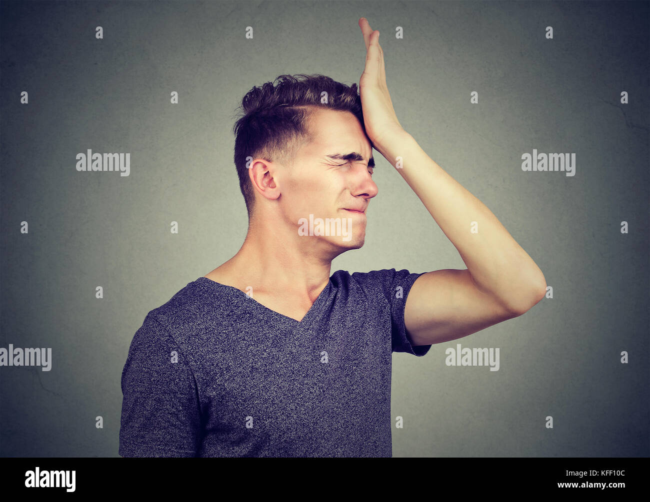 Man slapping hand on head having regrets isolated on gray background ...