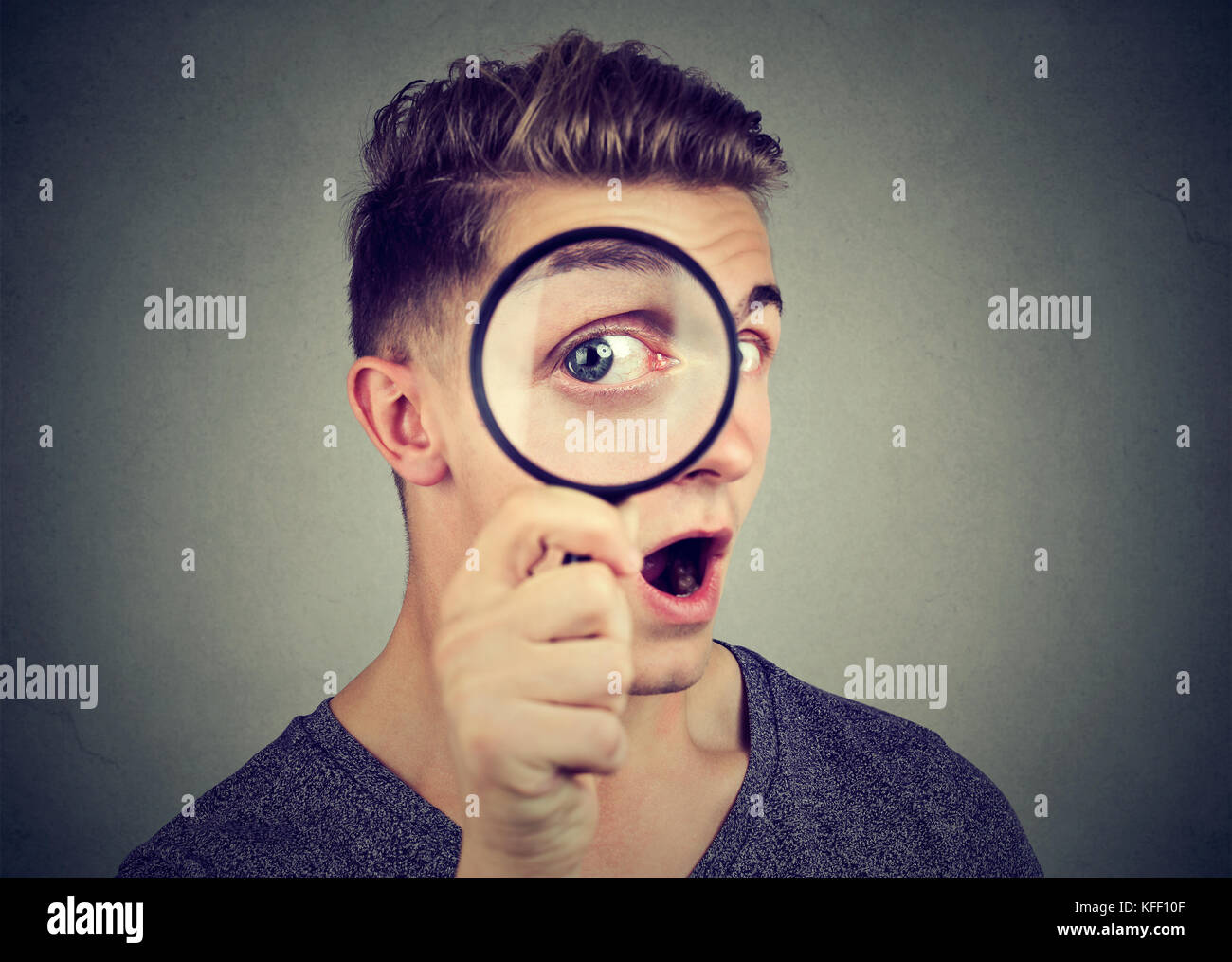 Curious man looking through a magnifying glass Stock Photo - Alamy