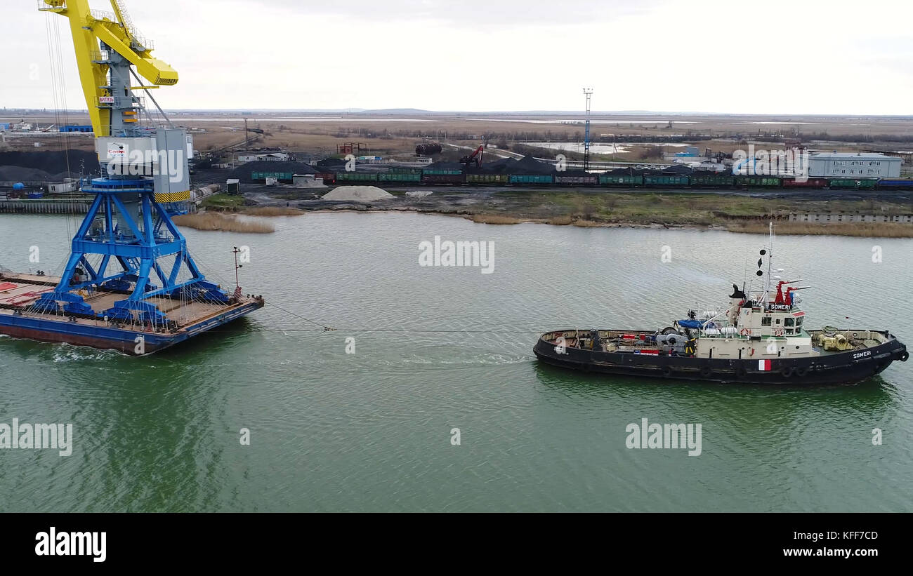 Towing cranes for containers. Large container ship pulled by tugboats ...