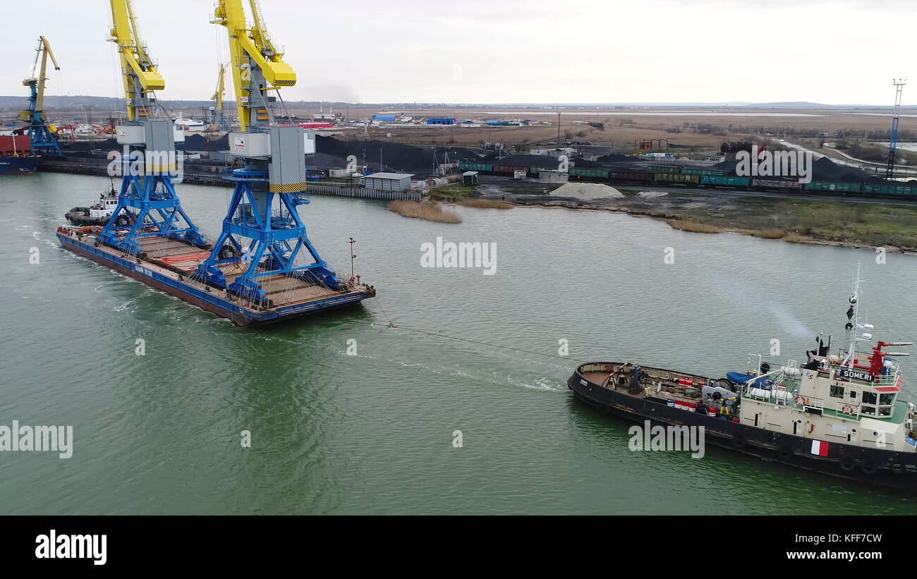 Towing cranes for containers. Large container ship pulled by tugboats ...