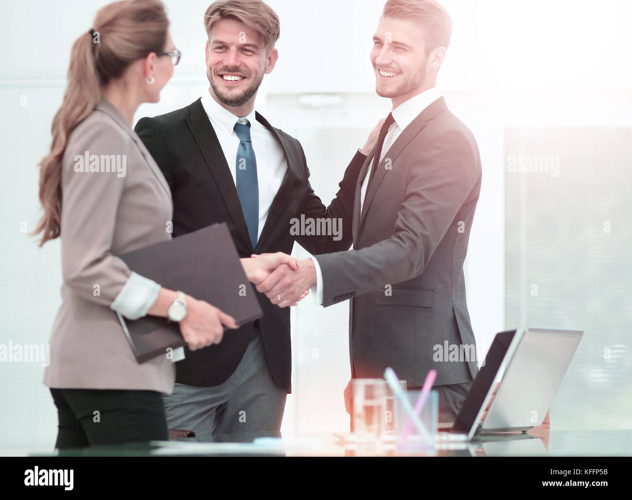 Successful business partners shaking hands with her colleagues on ...