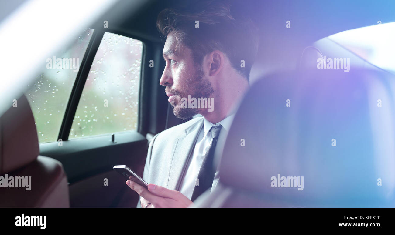 Handsone successful businessman using mobile phone in back seat of car ...