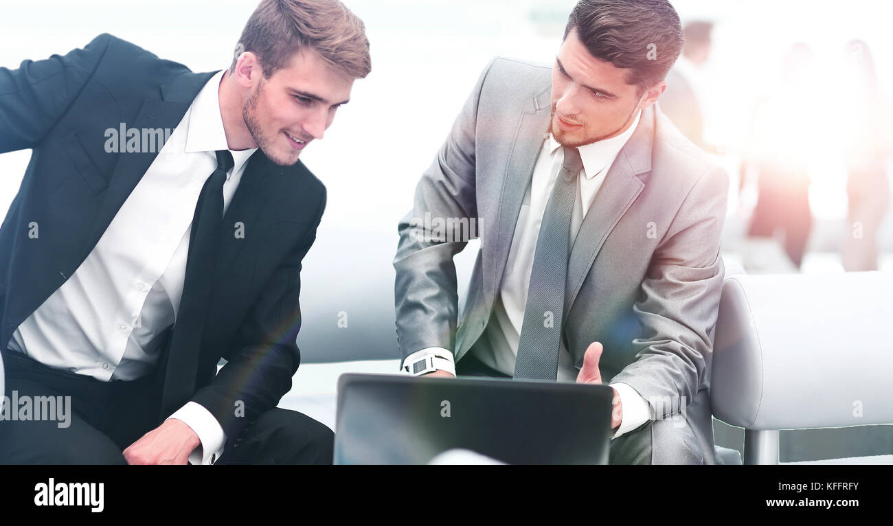 Smiling business men showing something on computer as colleague looking ...