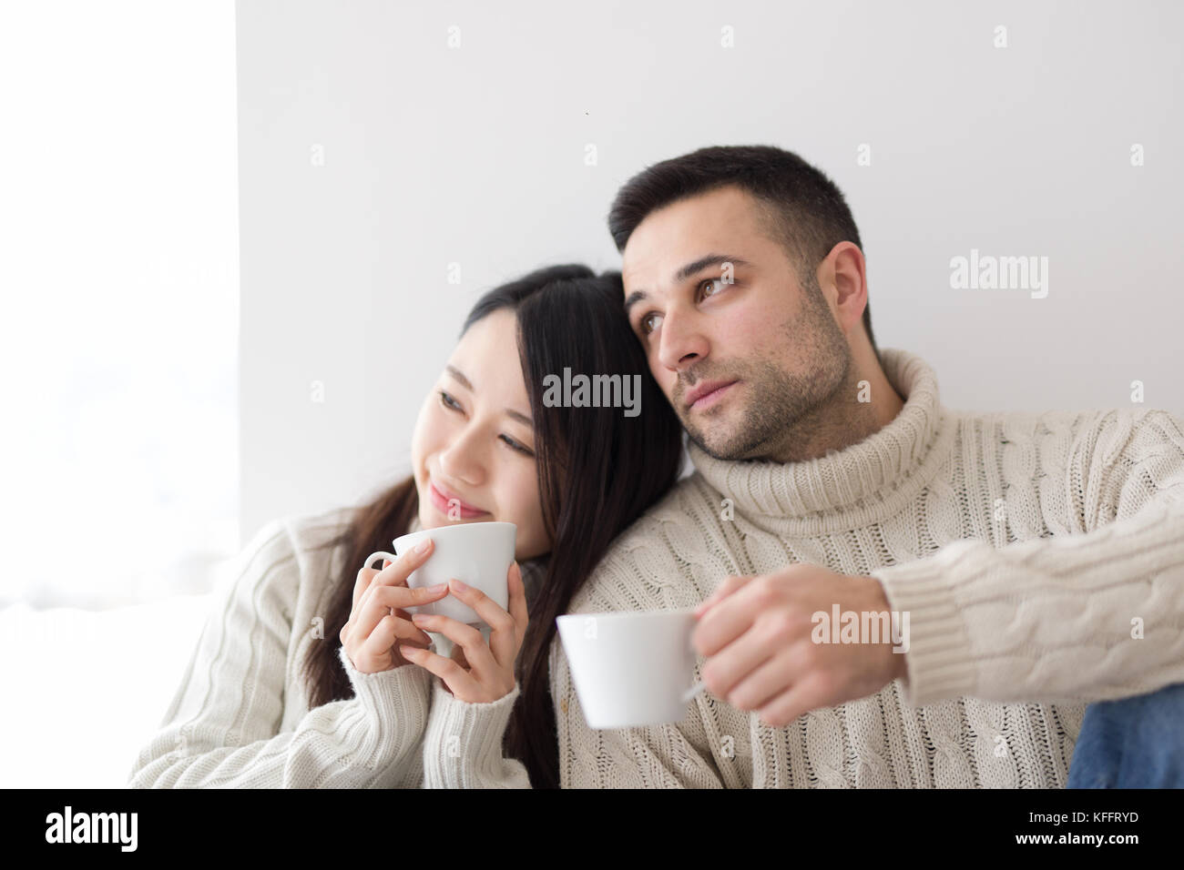 happy young multiethnic couple enjoying morning coffee by the window on ...