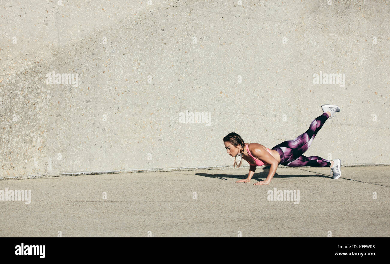 Young muscular woman doing core exercise. Fit female doing press-ups ...