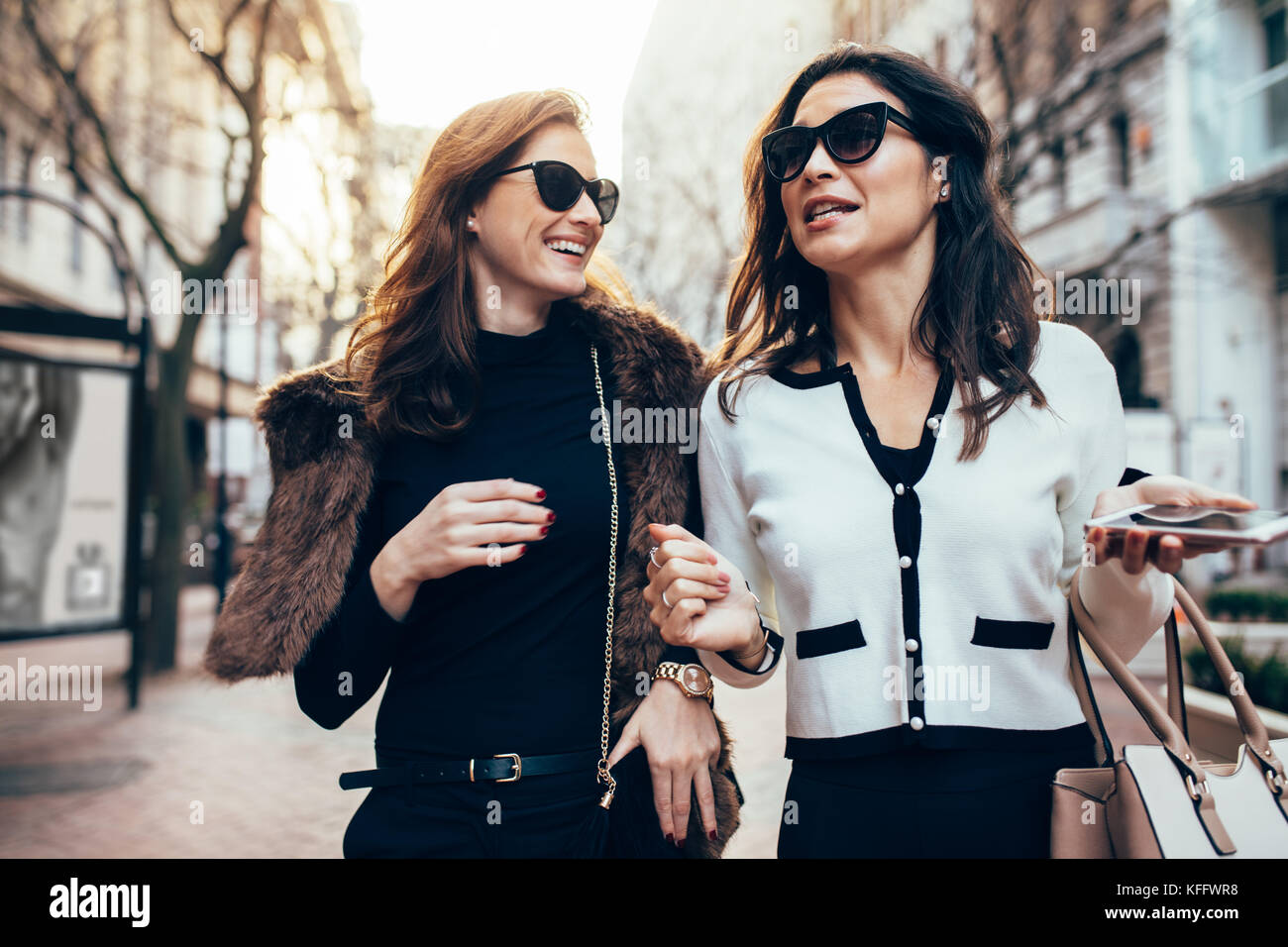 Two females walking together on the city street. Women friends walking ...