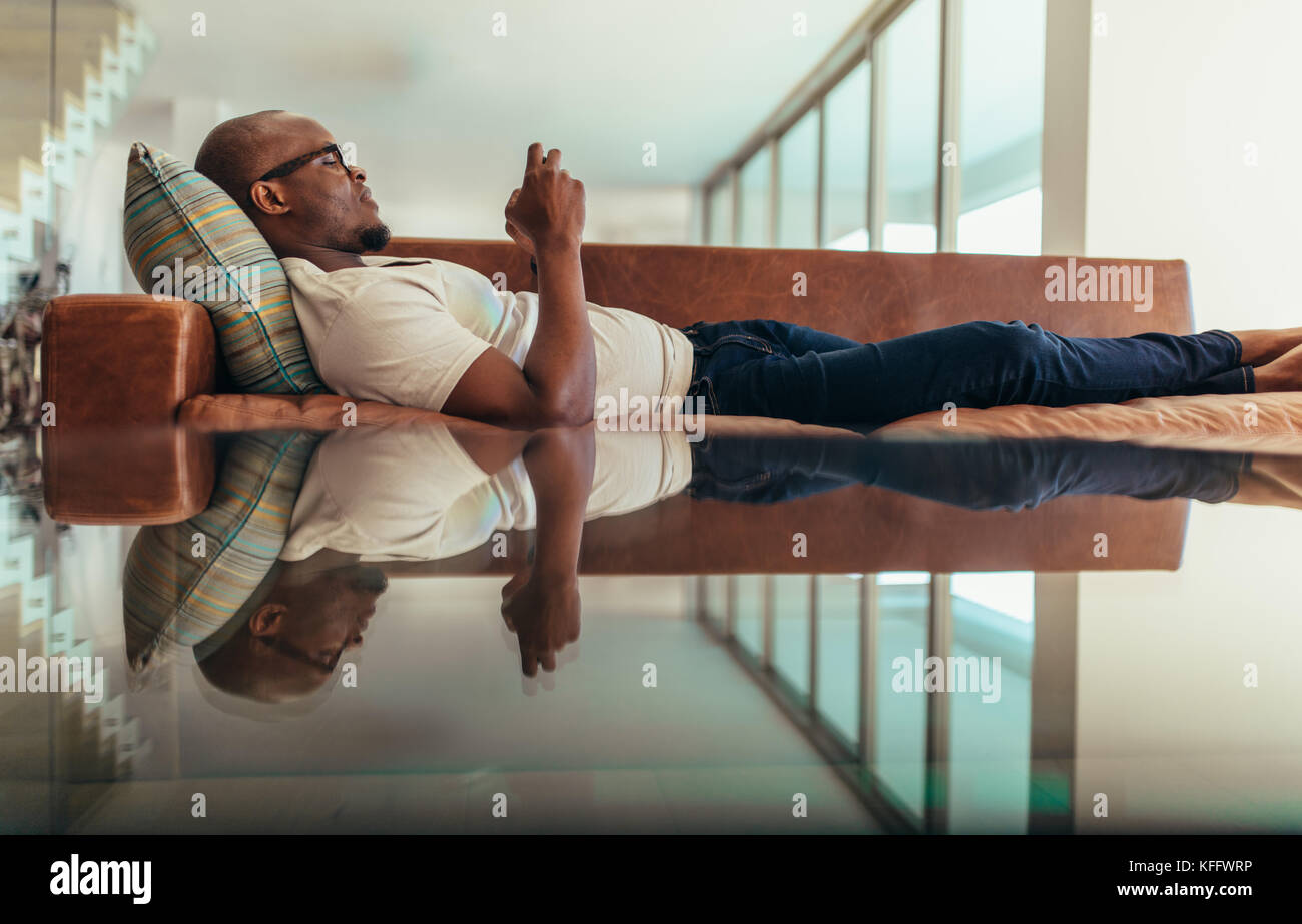 Man relaxing on a lounge and operating mobile phone. Symmetrically ...