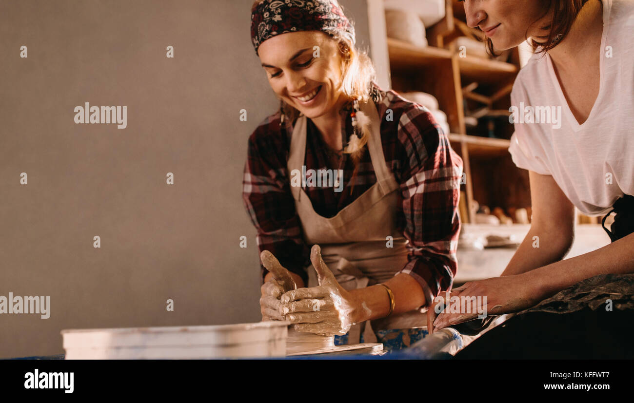 Woman potter teaching the art of pot making. Two women at a pottery ...