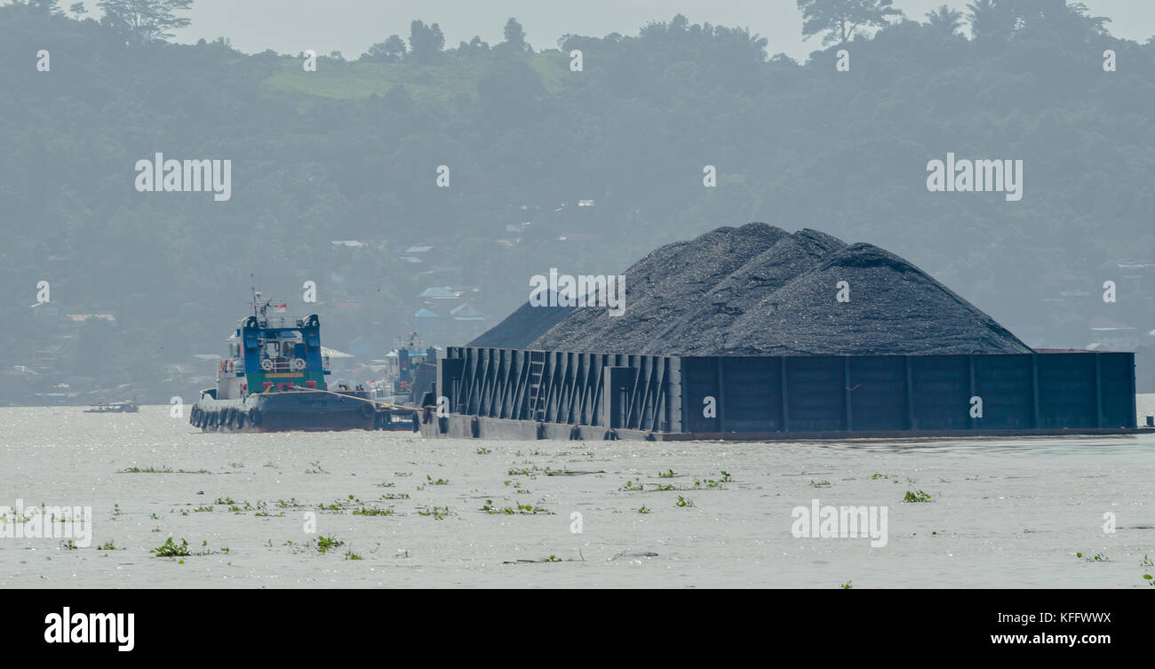 tugboat pulling heavy loaded barge of black coal in the river Stock ...