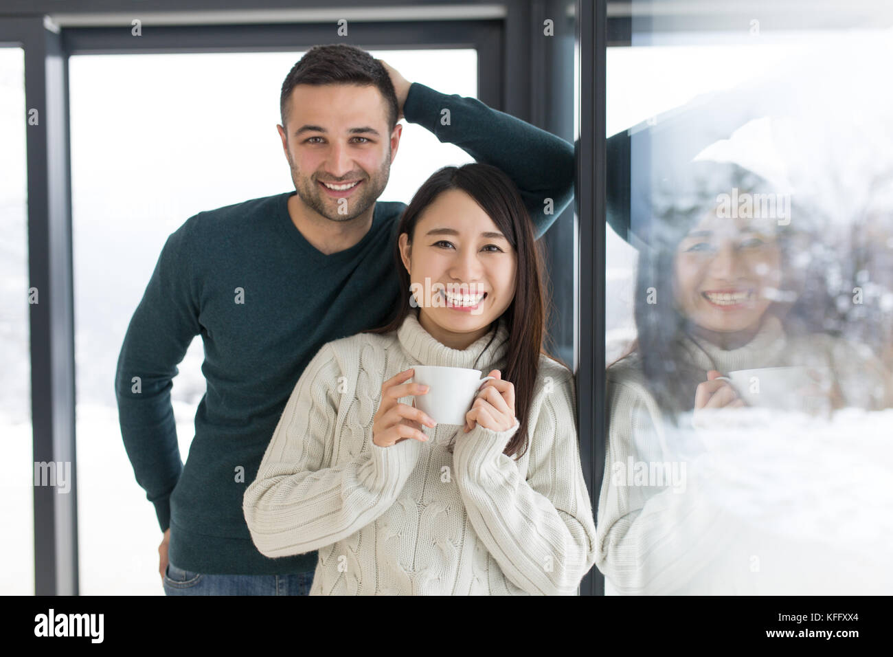 happy young multiethnic couple enjoying morning coffee by the window on ...