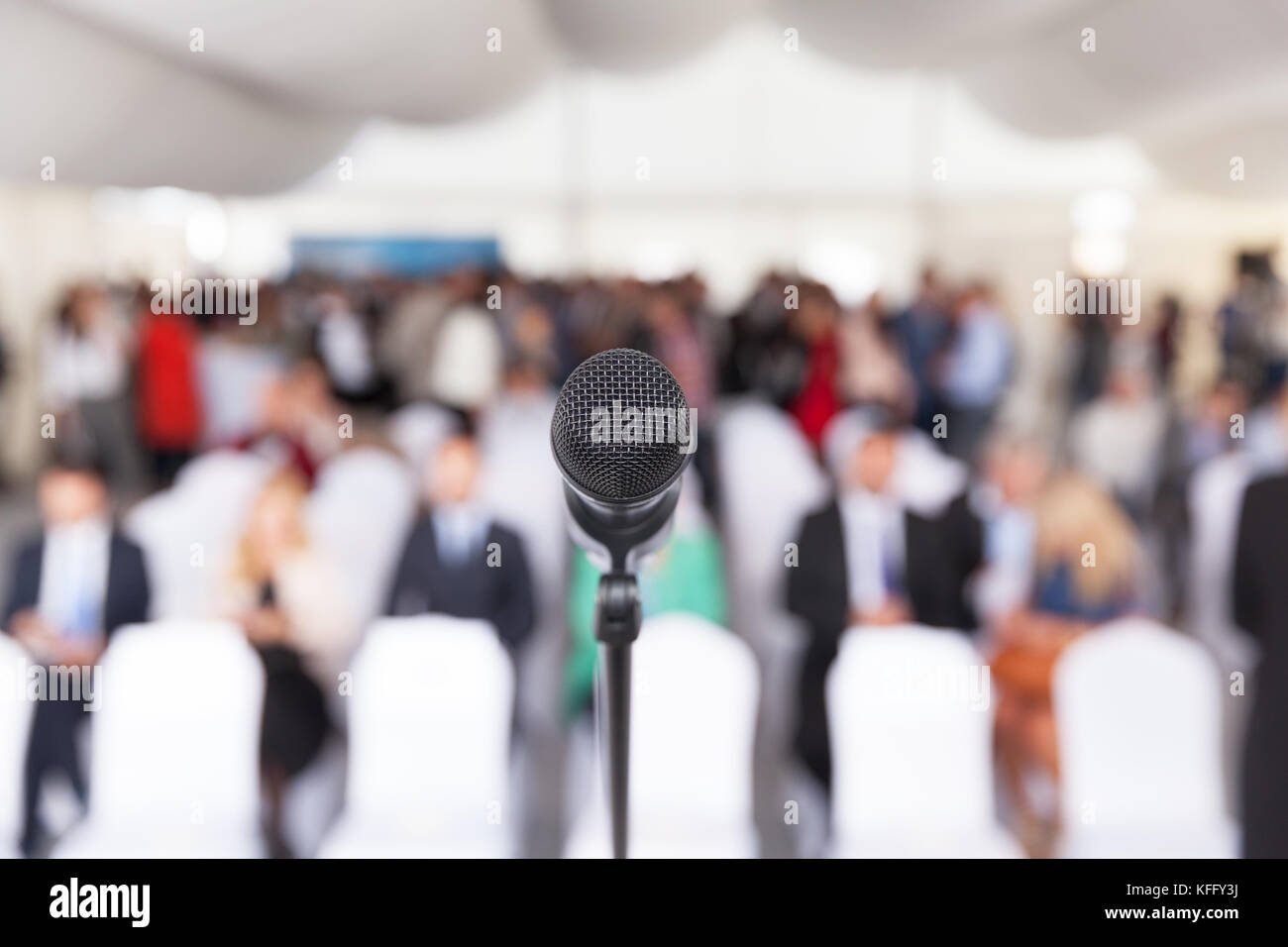 Microphone in focus against blurred audience. Participants at the ...