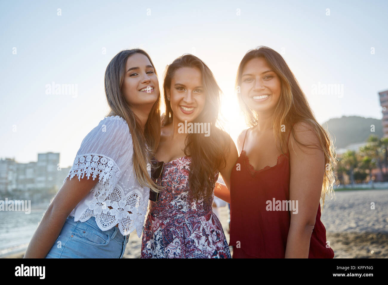 Portrait of three pretty girls standing on beach in sunlight Stock ...