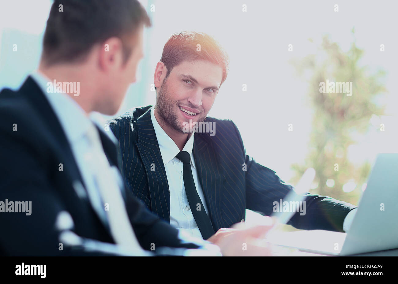 Two businessmen discussing tasks sitting at office table Stock Photo ...