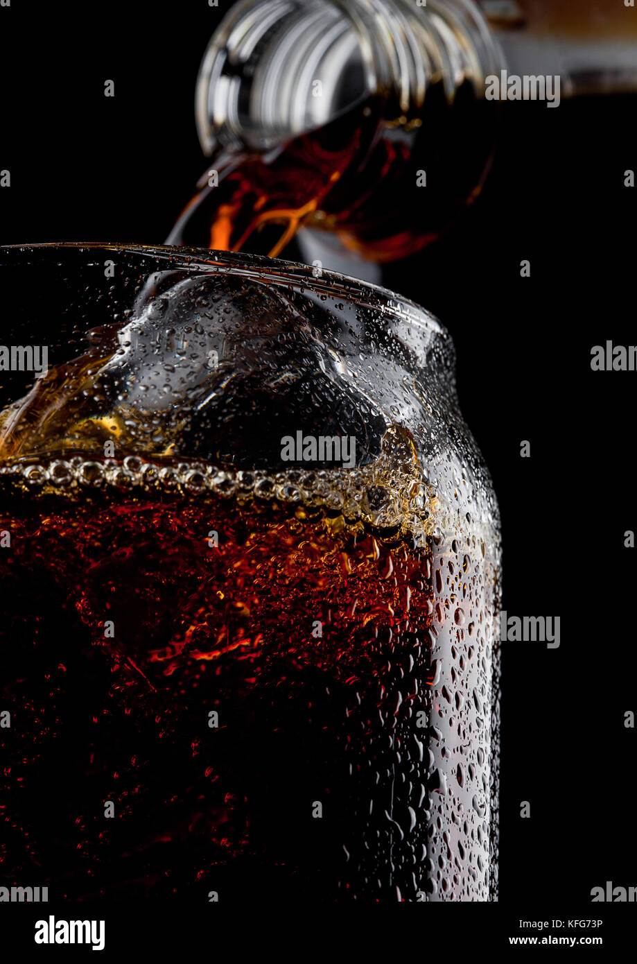 Glass of cold cola soda drink with ice cubes on black background. Macro ...