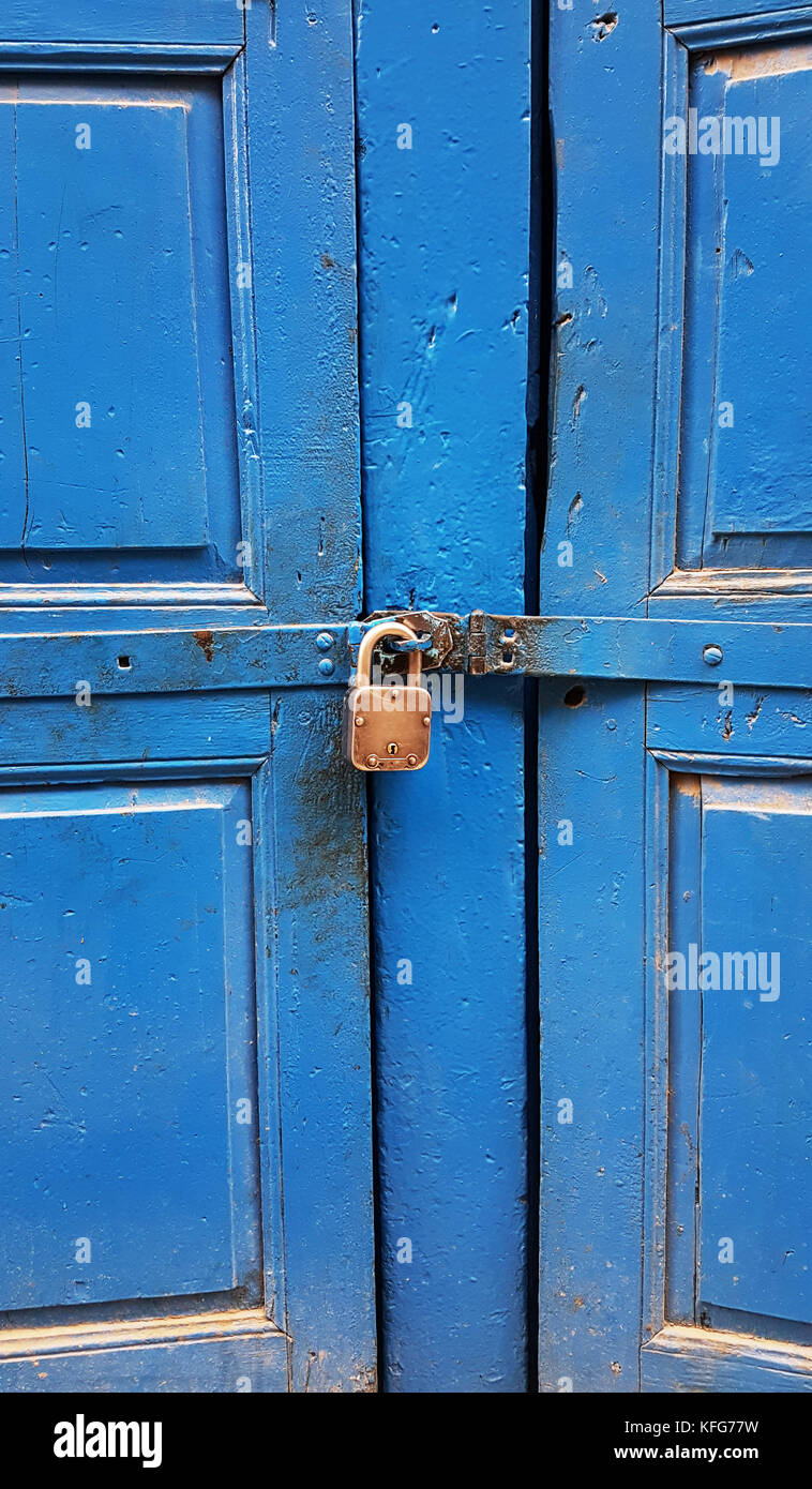 Rusty orange lock covers the wooden blue doors, rectangular frames on ...