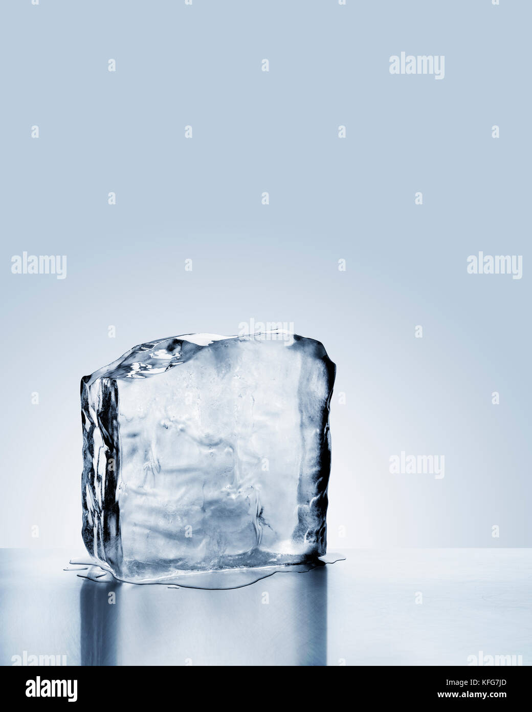Cold blue crystal clear frozen block of ice melting to create pool of ...