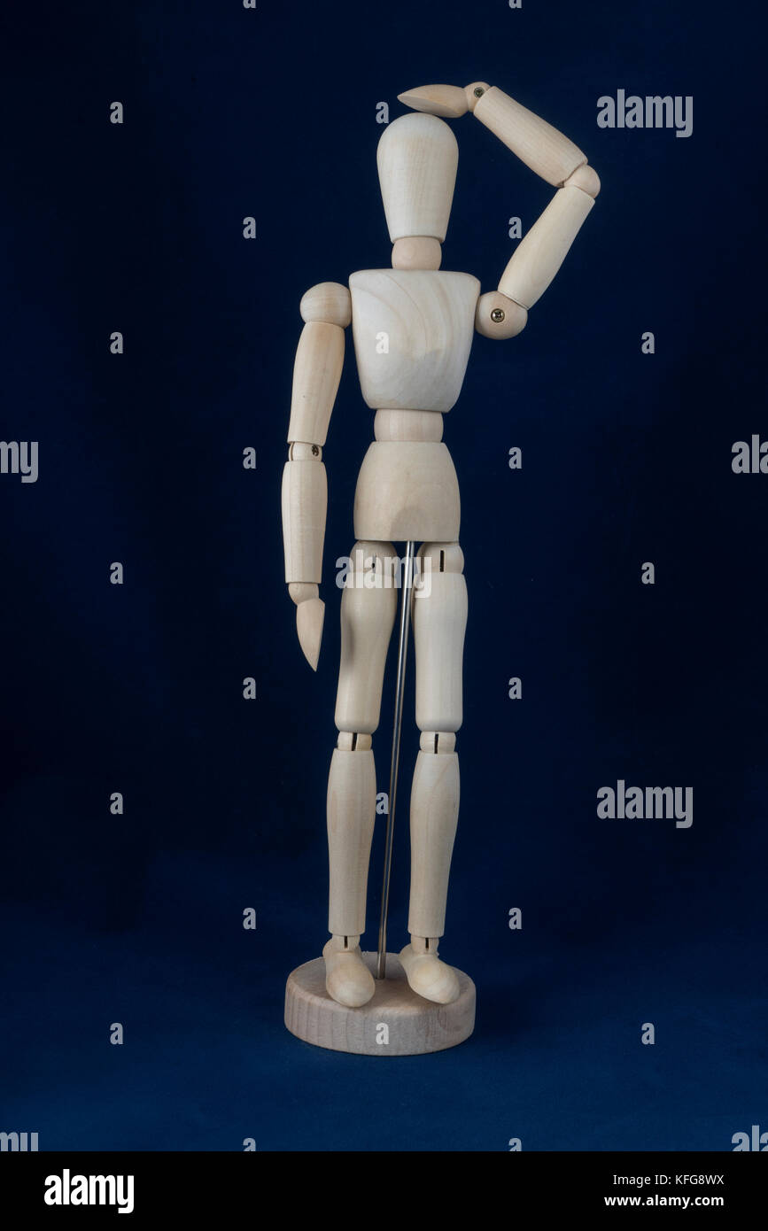 a wooden dummy posing standing with a blue background Stock Photo - Alamy