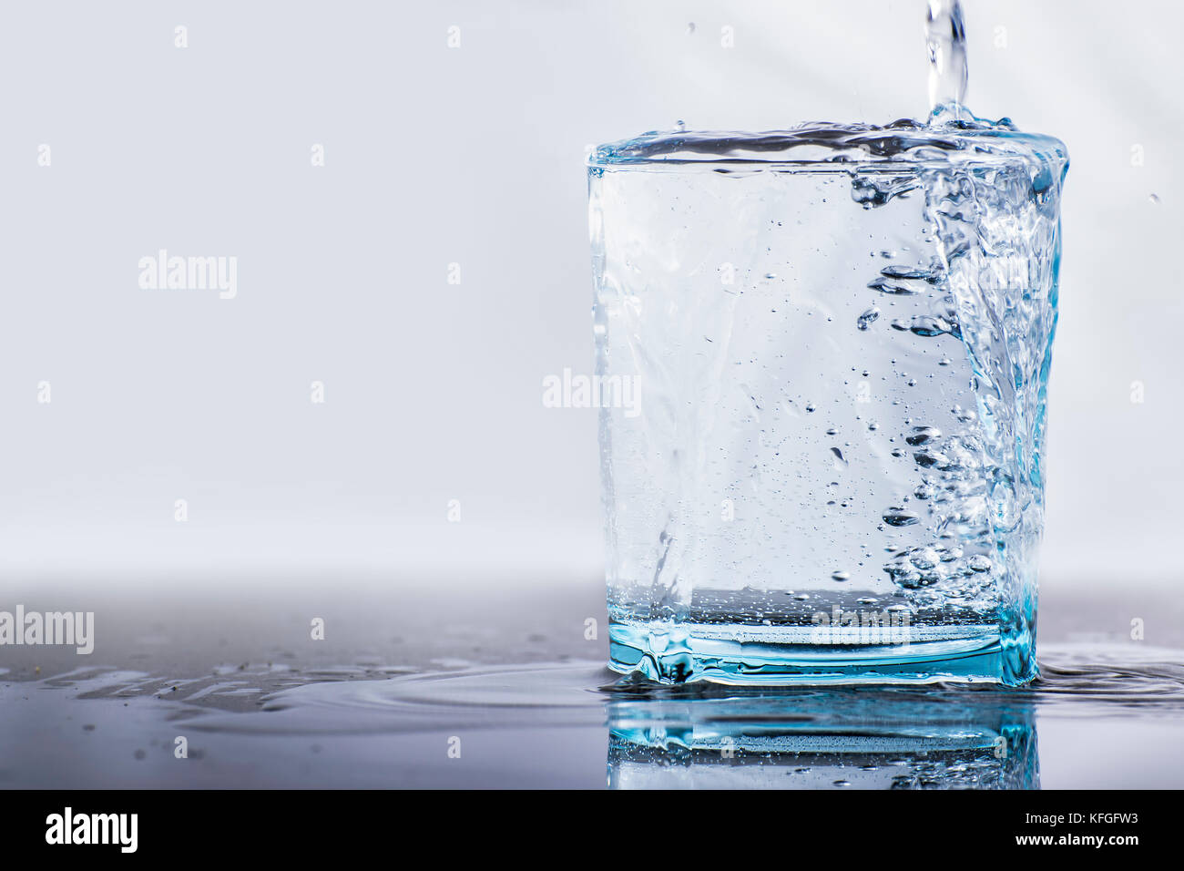 a glass filling of water, in a high key photography with a white bright ...