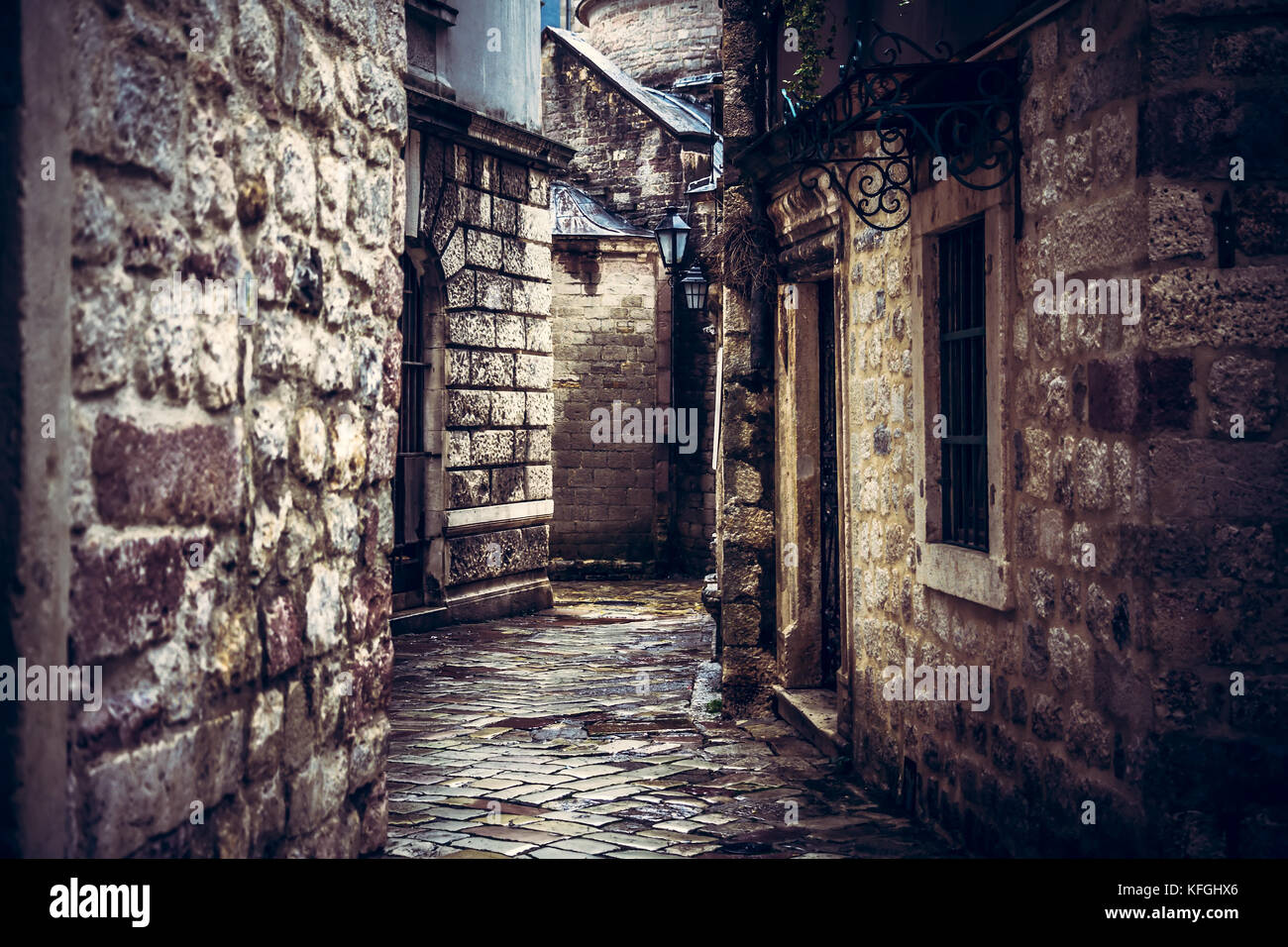 Dark vintage medieval narrow winding street with ancient stone building ...