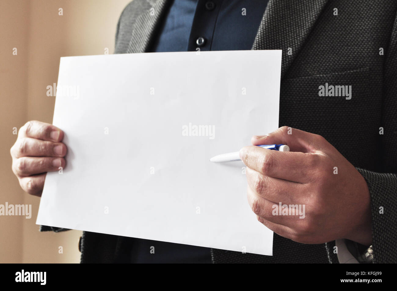 A businessman holding a sheet of white paper Stock Photo - Alamy