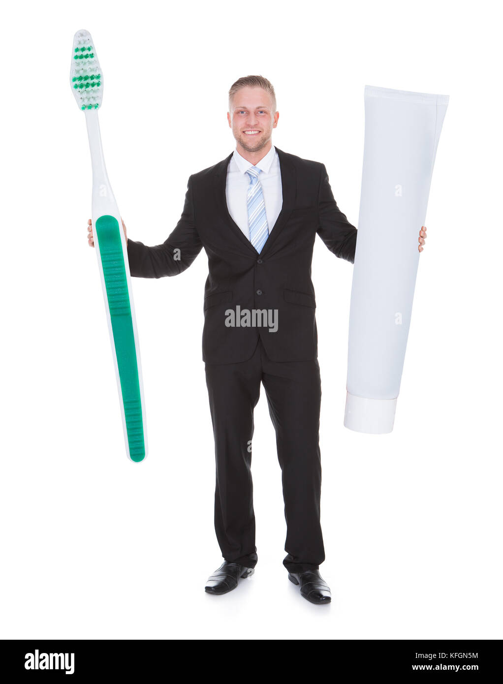 Smiling business man holding a large outsized toothbrush and blank ...