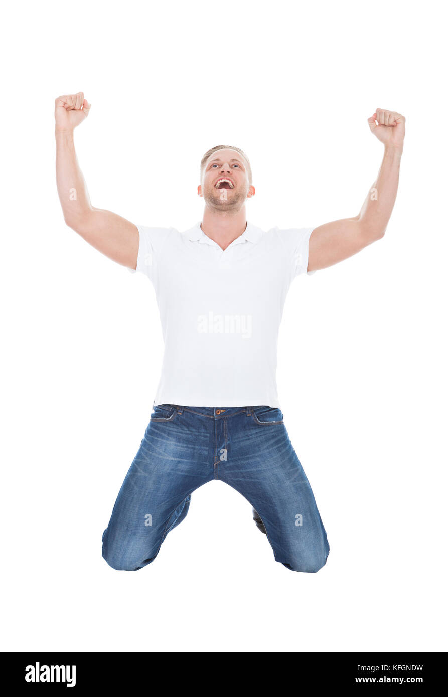 Excited man cheering in jubilation dropping down on his knees with his ...