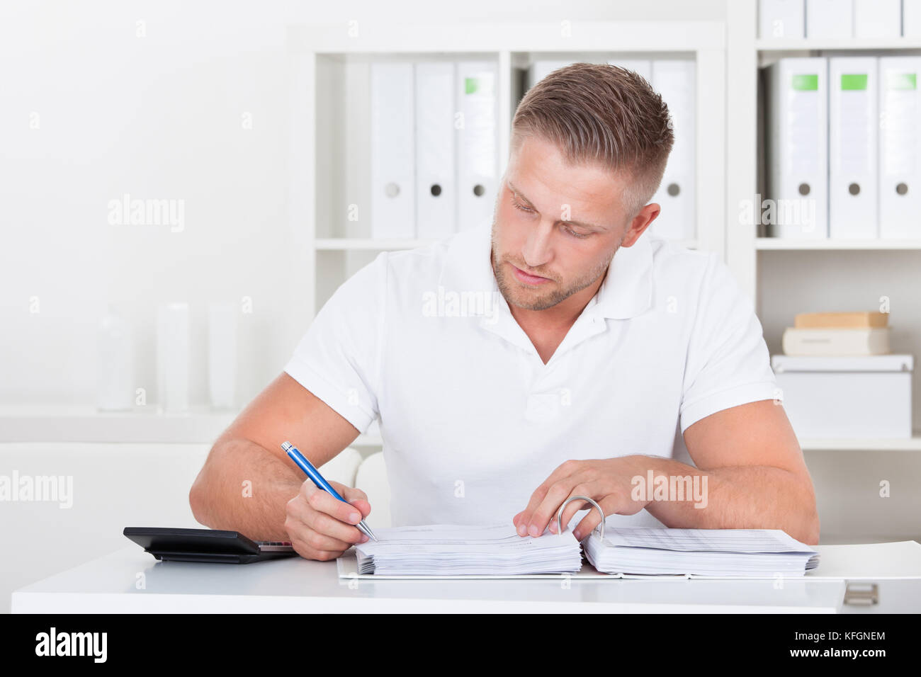 Businessman working at his desk in the office sitting writing notes in ...