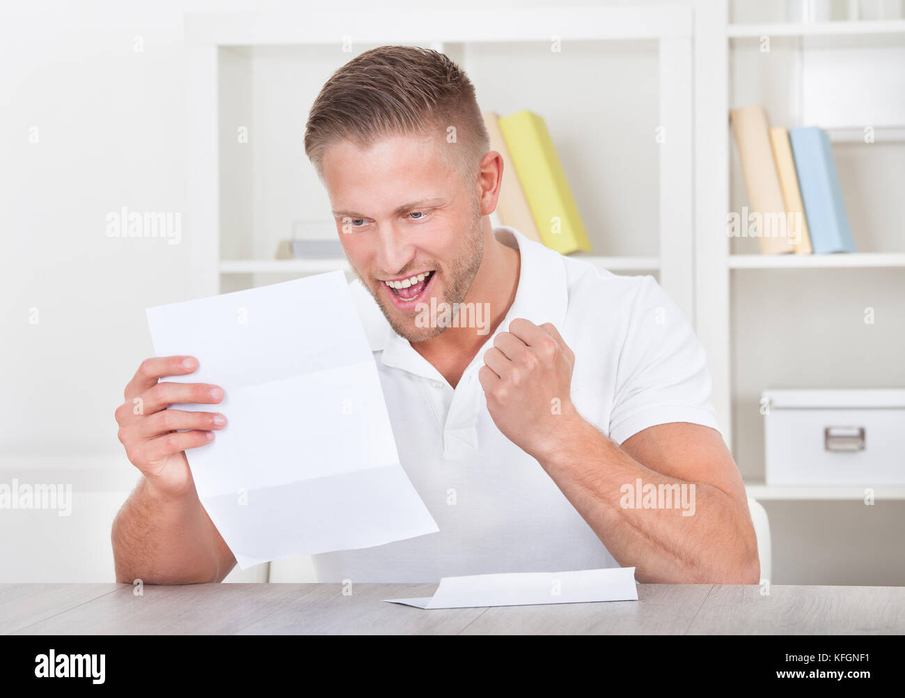 Man cheering in jubilation as he reads a letter punching the air with ...