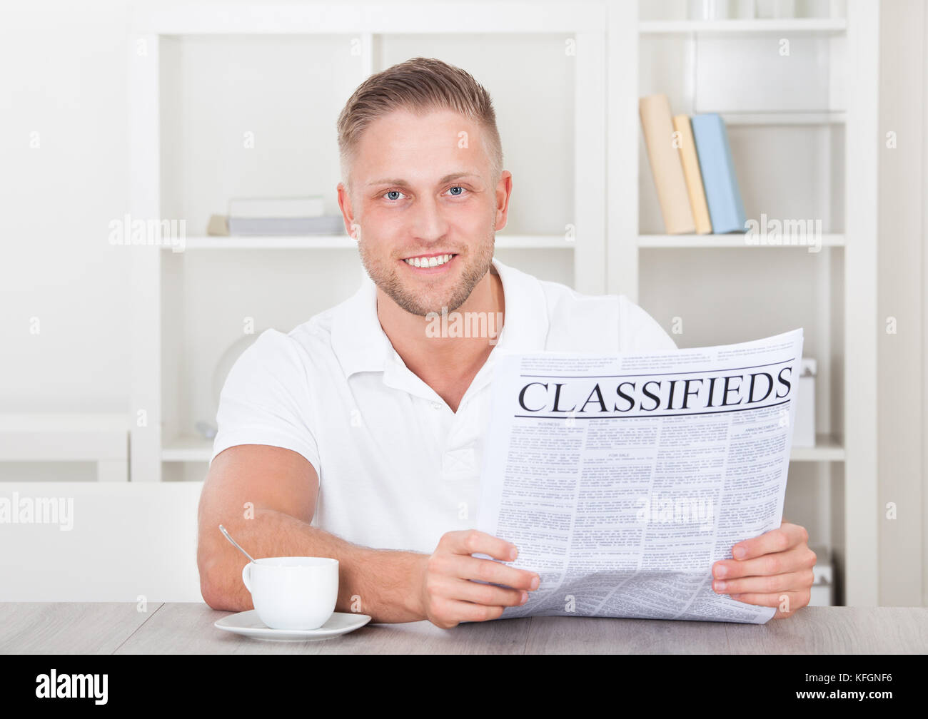 Excited man reading the classifieds cheering as he comes across good ...