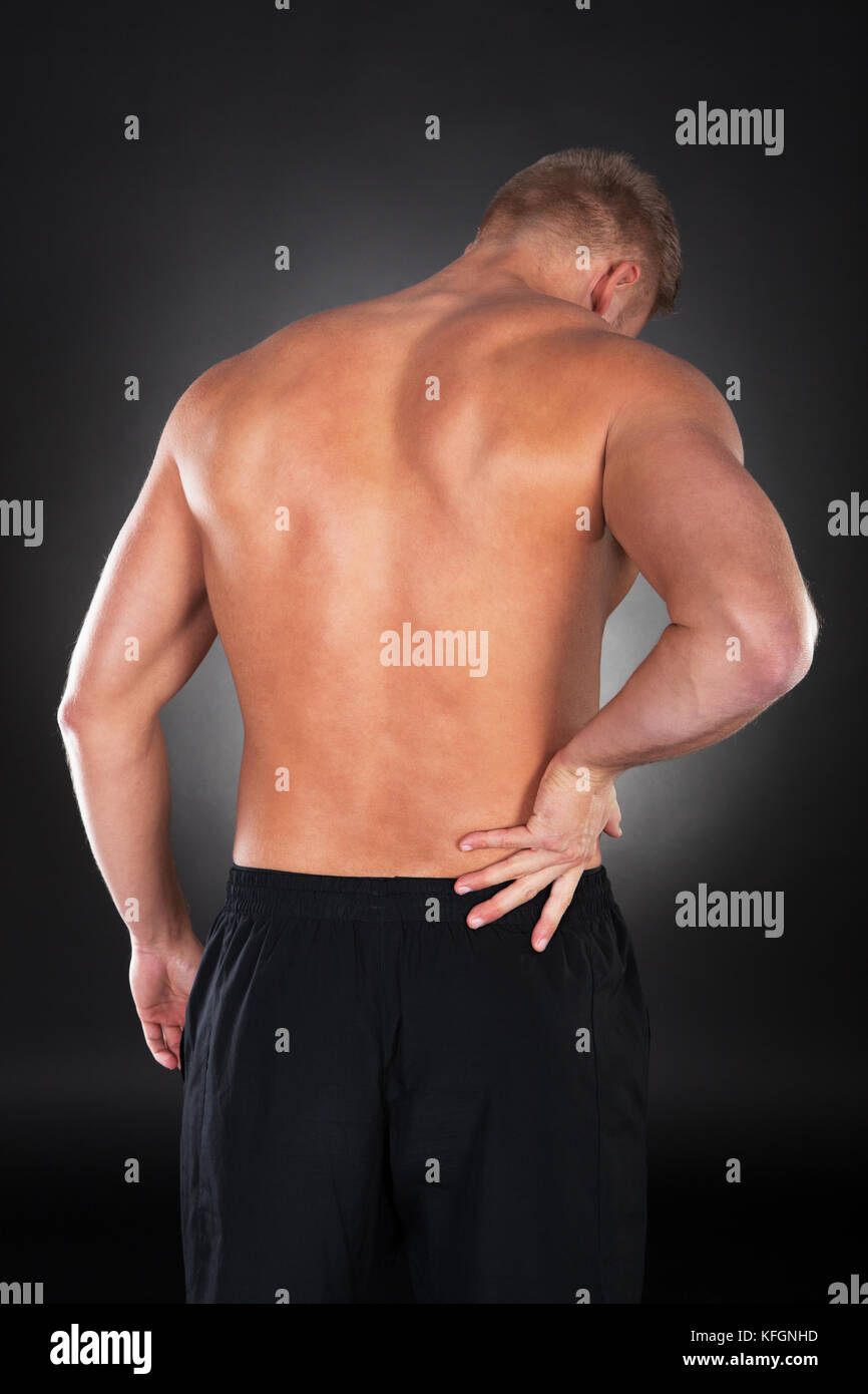 View from behind of a shirtless strong muscular man with backache ...