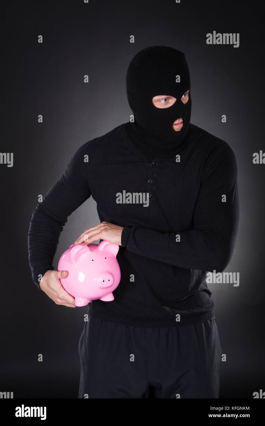 Furtive thief or burglar wearing a black outfit and balaclava making ...