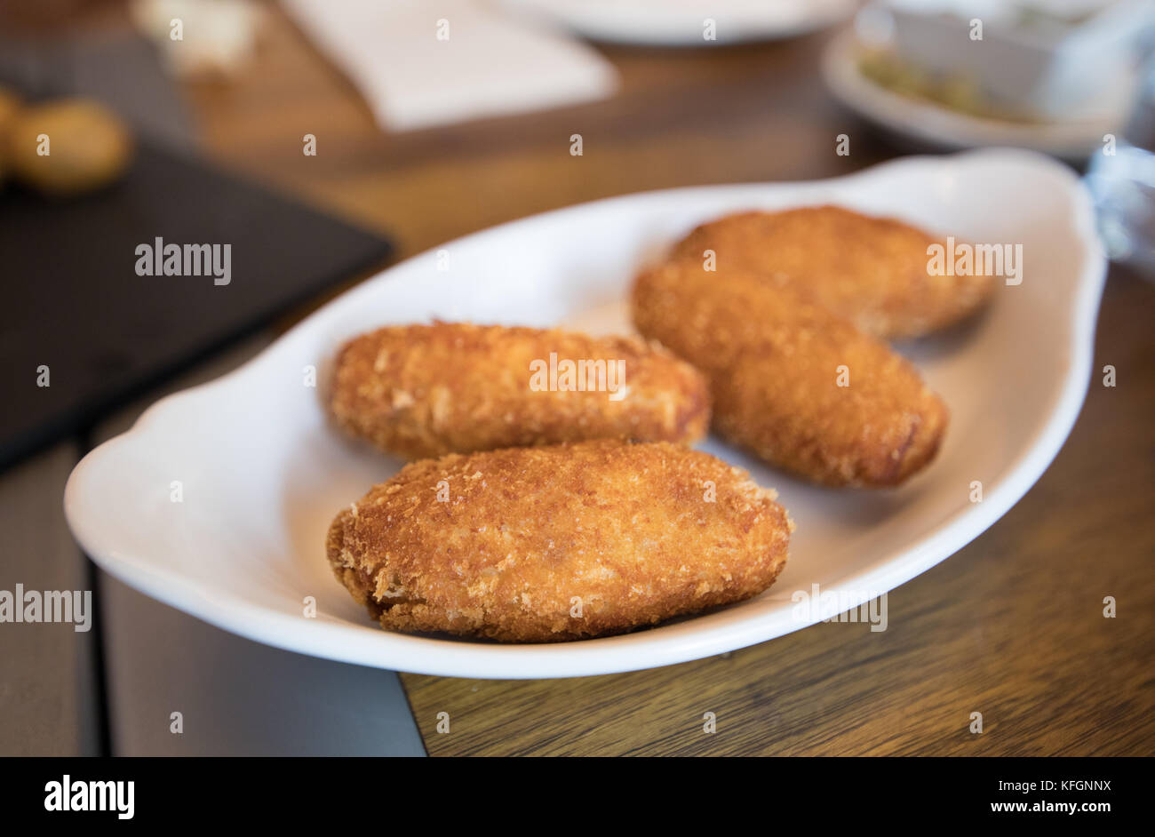 close up still life four croquettes in white tray over brown table at ...