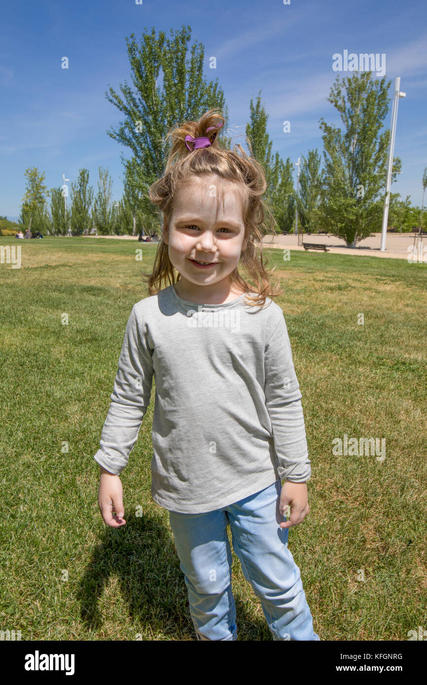 funny portrait of blonde three years old child with pigtail, grey shirt ...