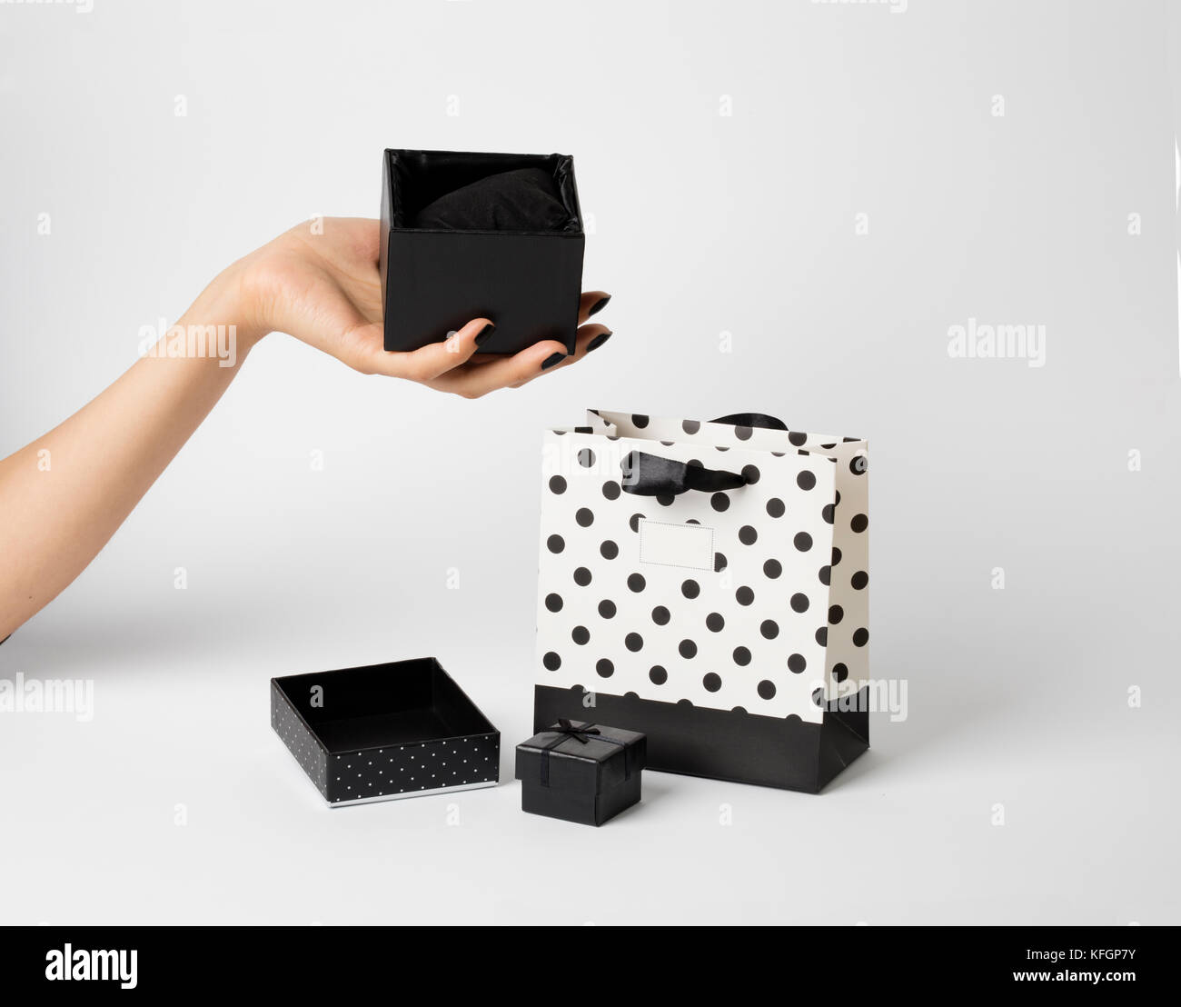 Female hand holding an opened, empty gift box. Another closed box, a ...