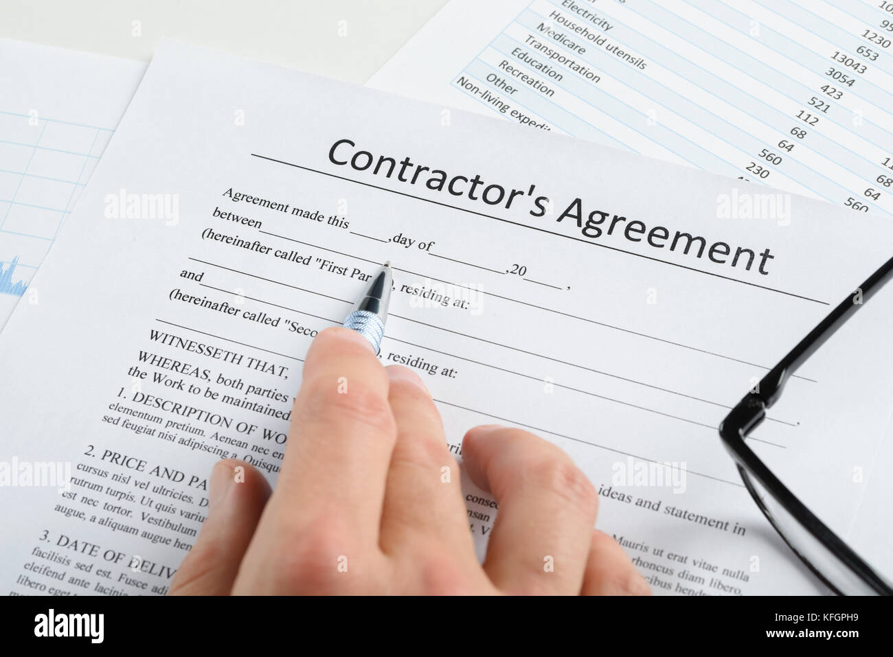 Close-up Of Hand With Pen And Eyeglasses Over Contractor Agreement ...