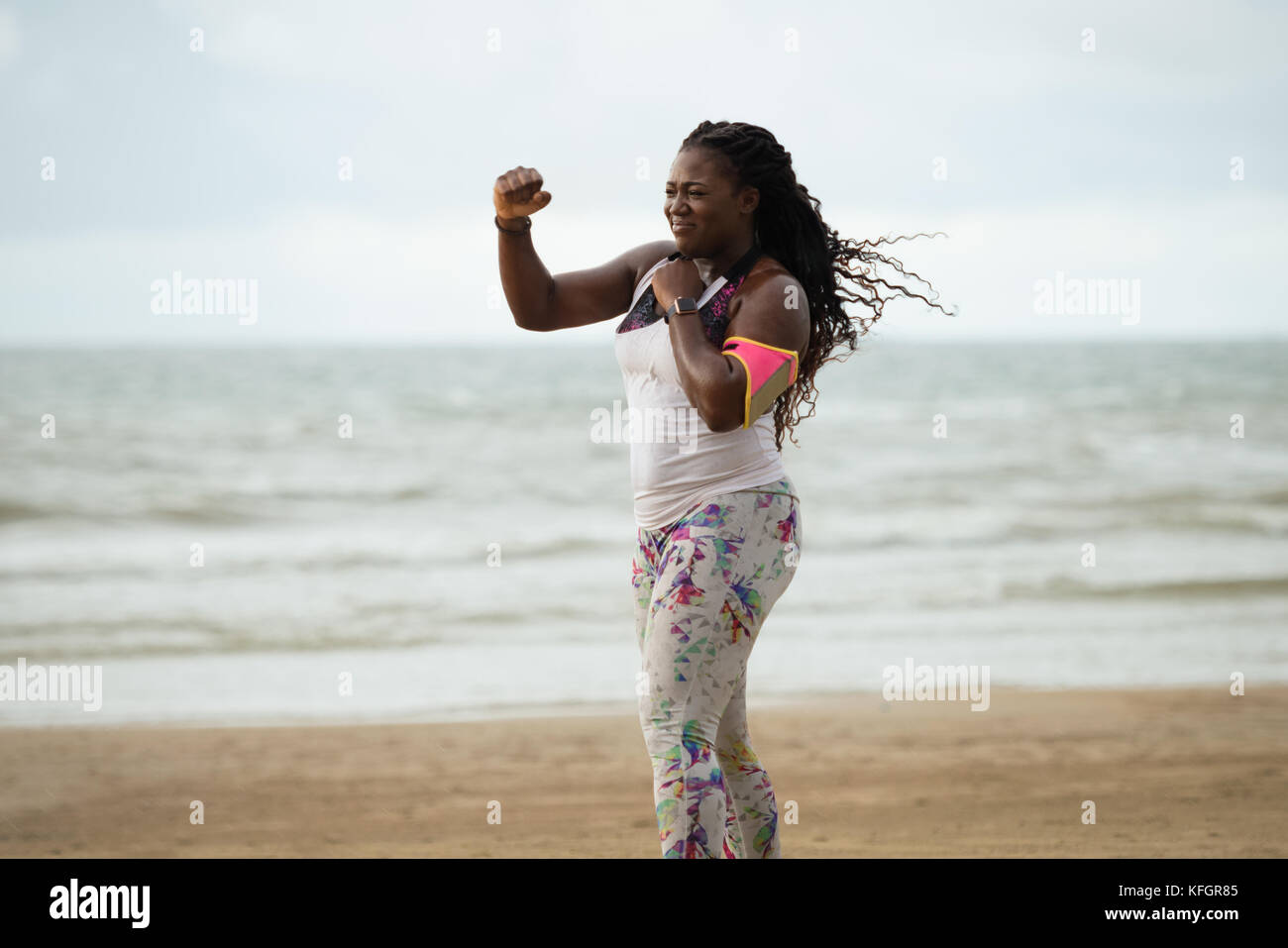 Sporty attractive african woman doing boxing exercises on the beach ...