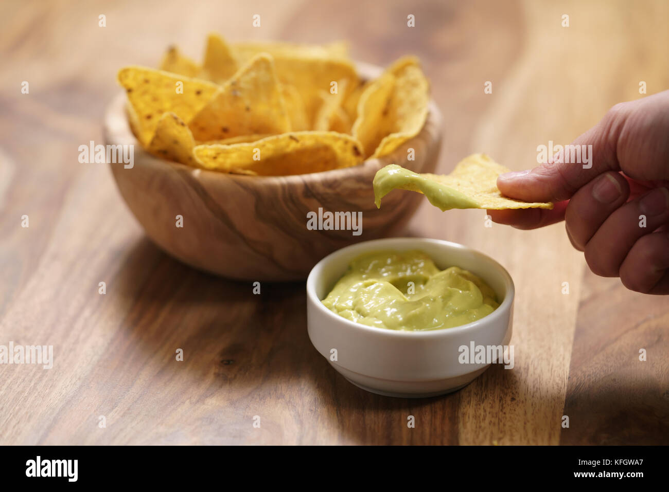 young female hand dipping nachos in guacamole sauce, shallow focus ...