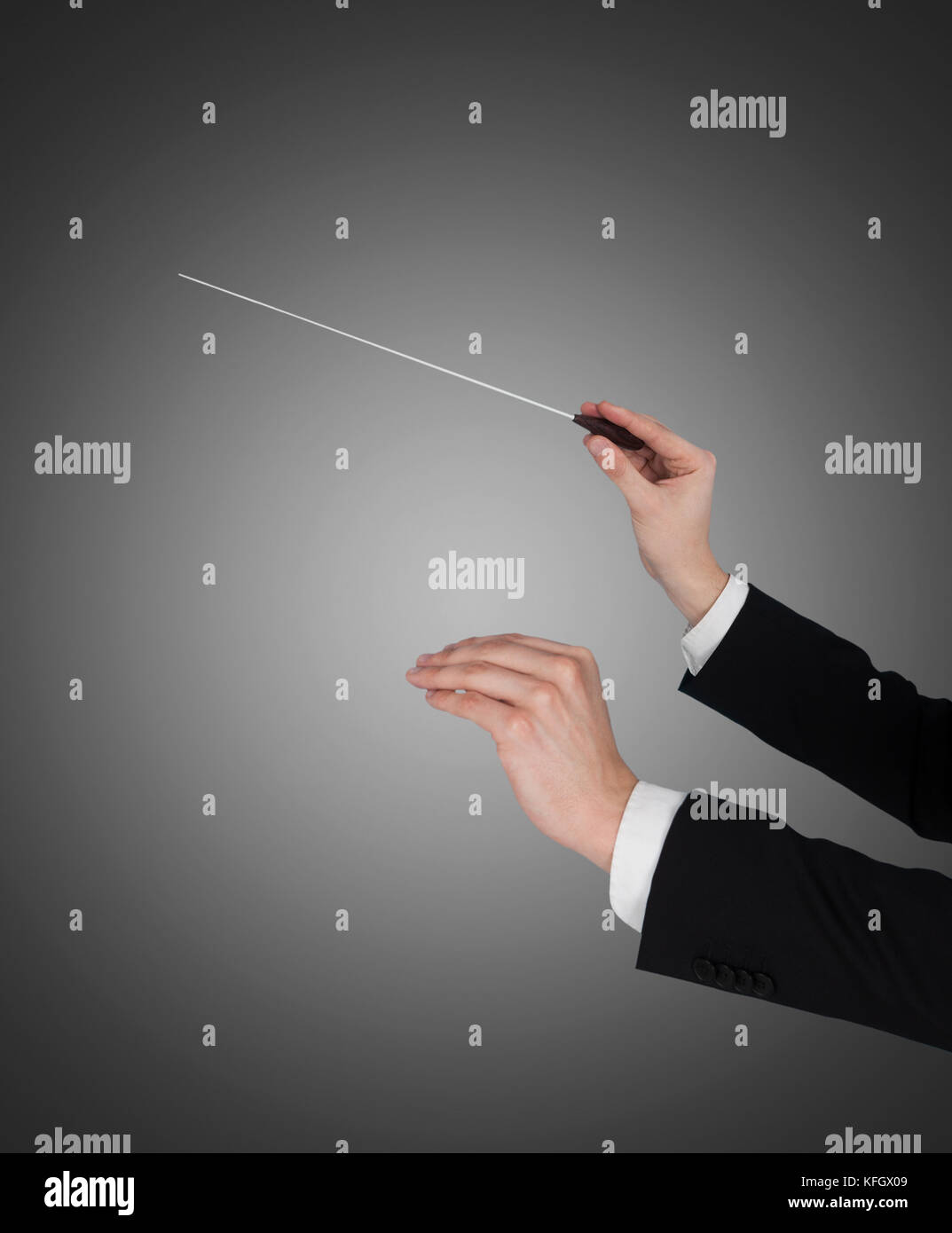 Closeup of music conductor's hands holding baton against gray ...