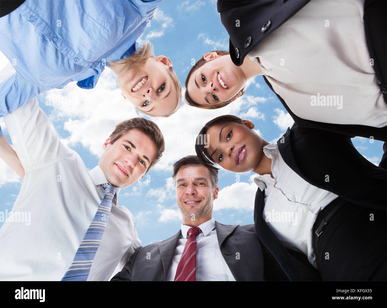 Low angle portrait of multiethnic business people forming huddle ...
