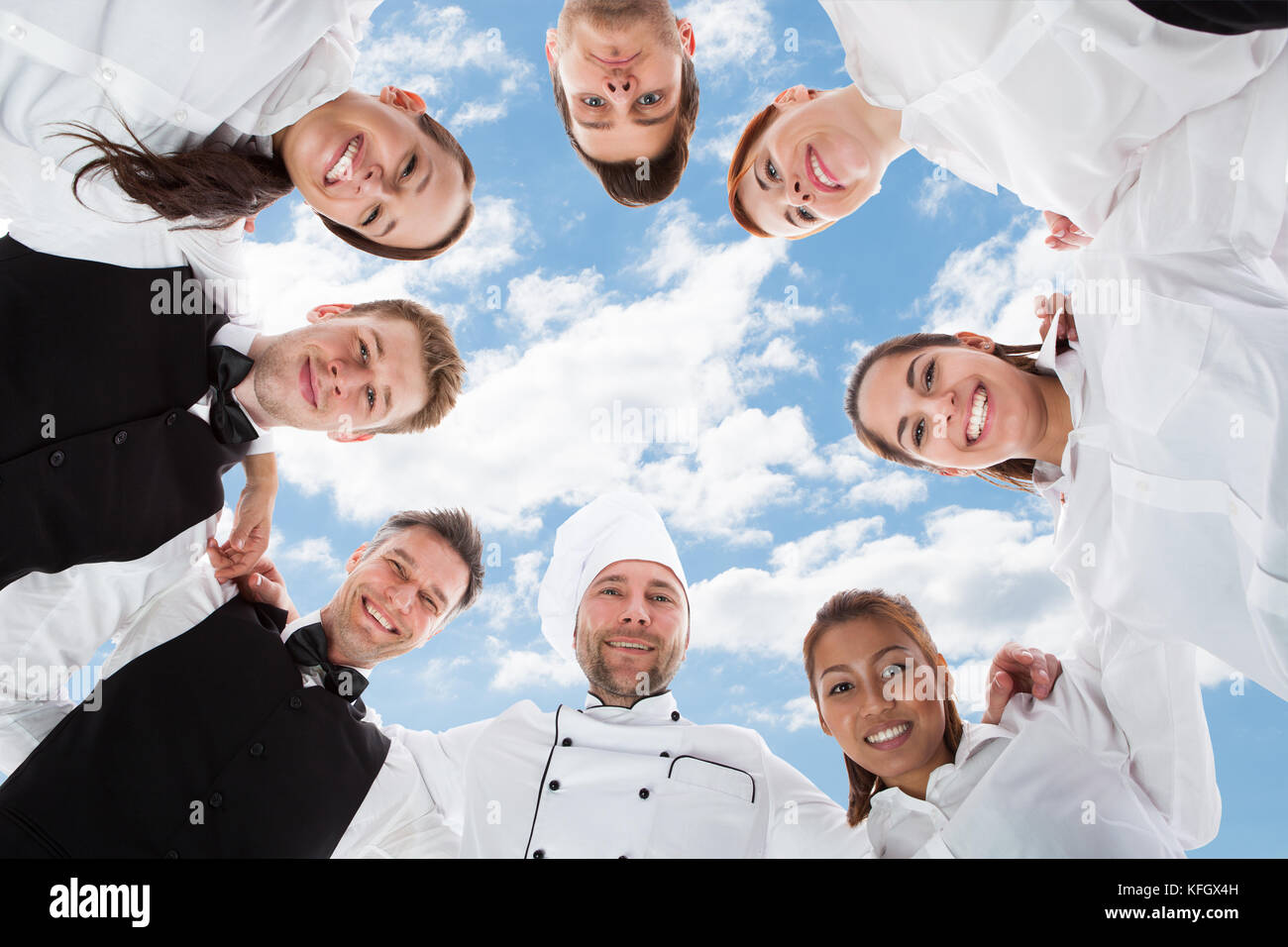 Directly below portrait of happy chef and waiters standing in huddle ...