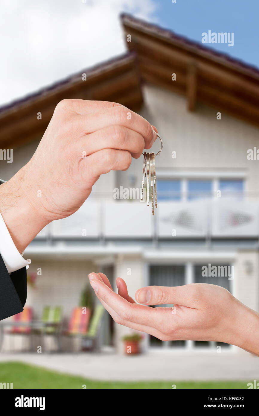 Cropped image of real estate agent giving keys to owner against new ...